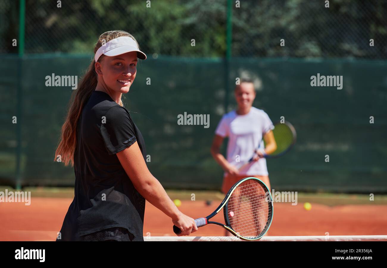 Young girls in a lively tennis match on a sunny day, demonstrating ...