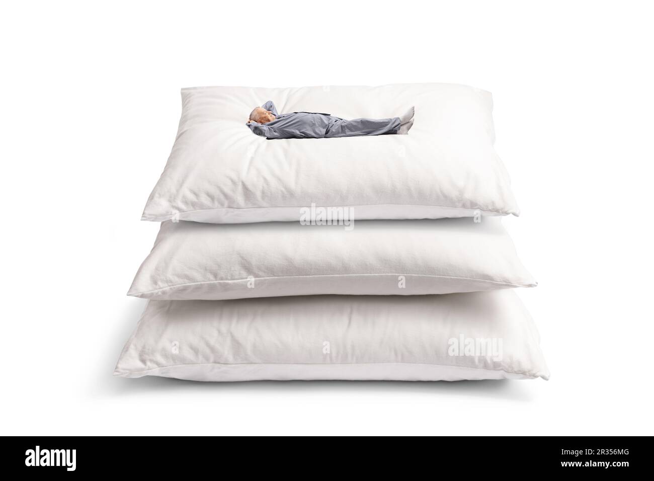 Mature man in pyjamas lying on a pile of pillows isolated on white ...