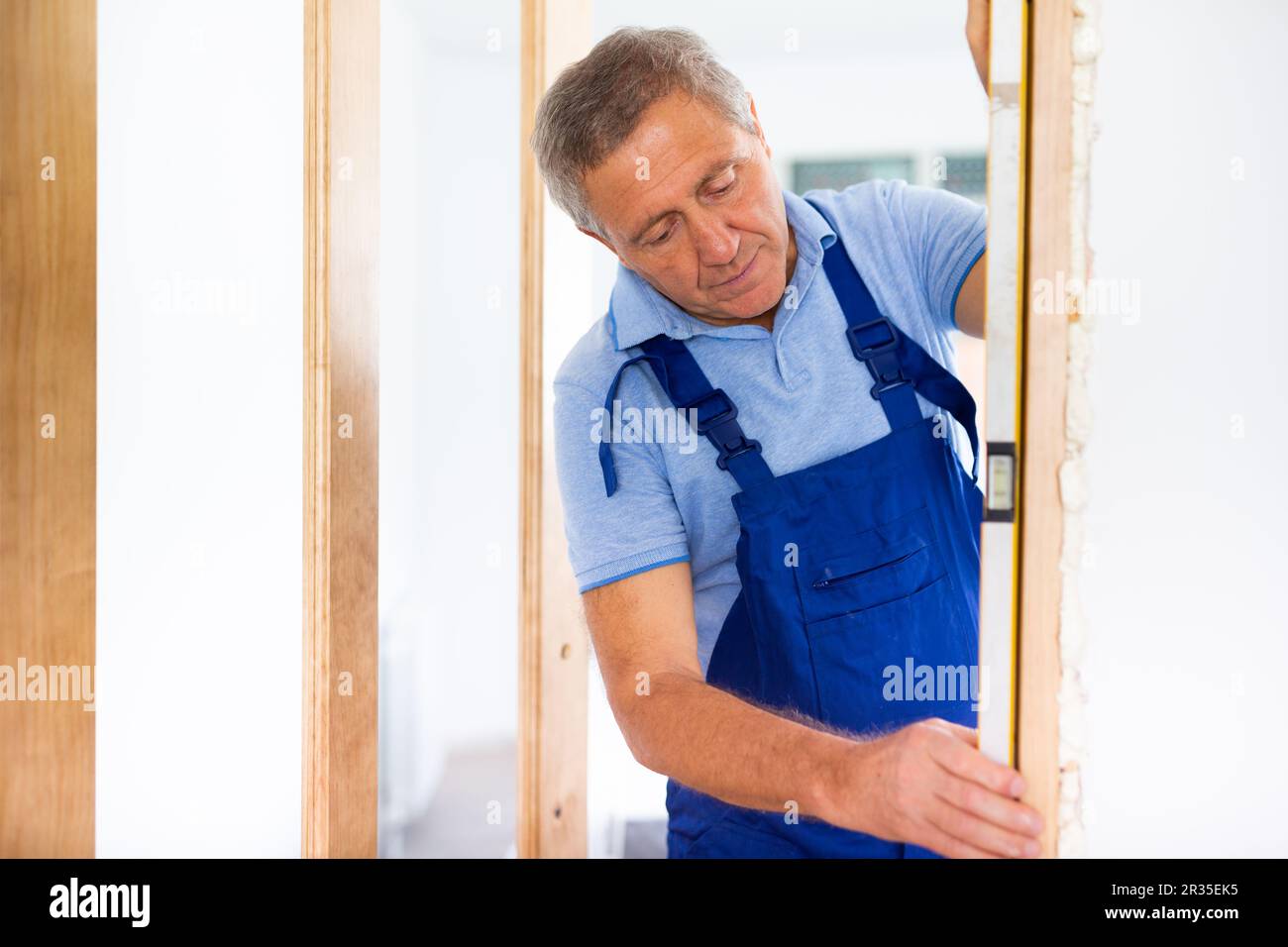 Man builder in blue overalls measures deviations from a given vertical ...