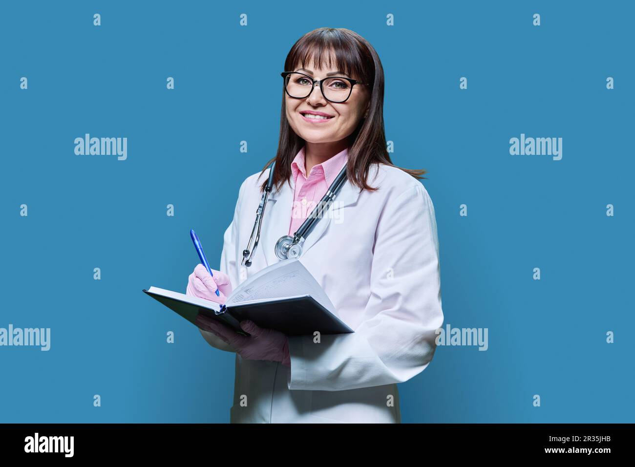 Female doctor taking note information in notebook on blue background ...