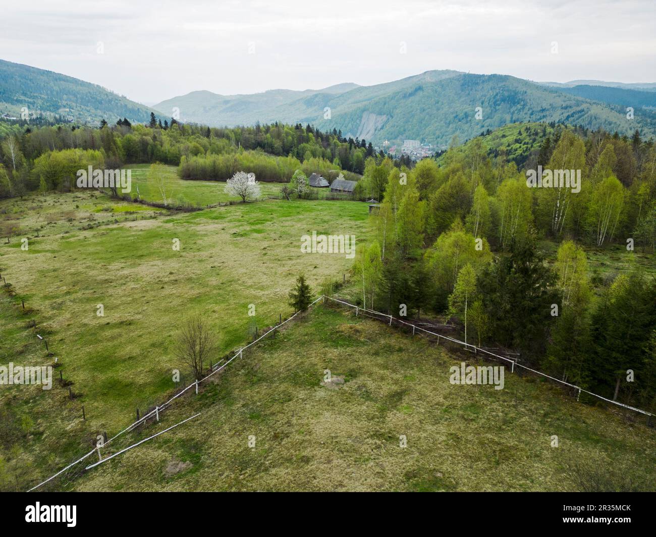 An aerial view of a farm with a fenced area in the green Carpathian ...
