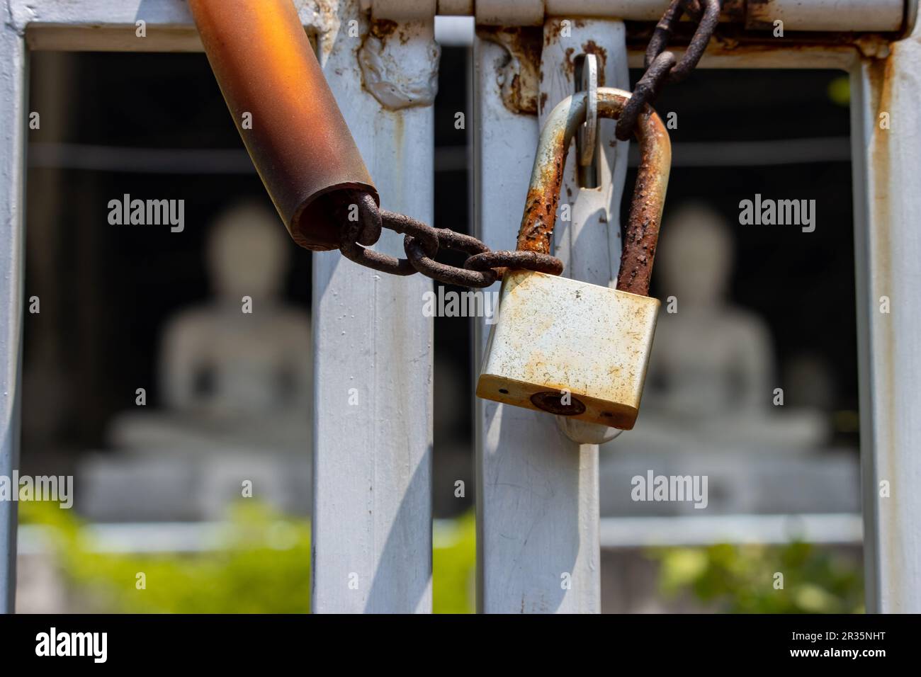 A locked gate in front of a building with seated Buddha statues ...