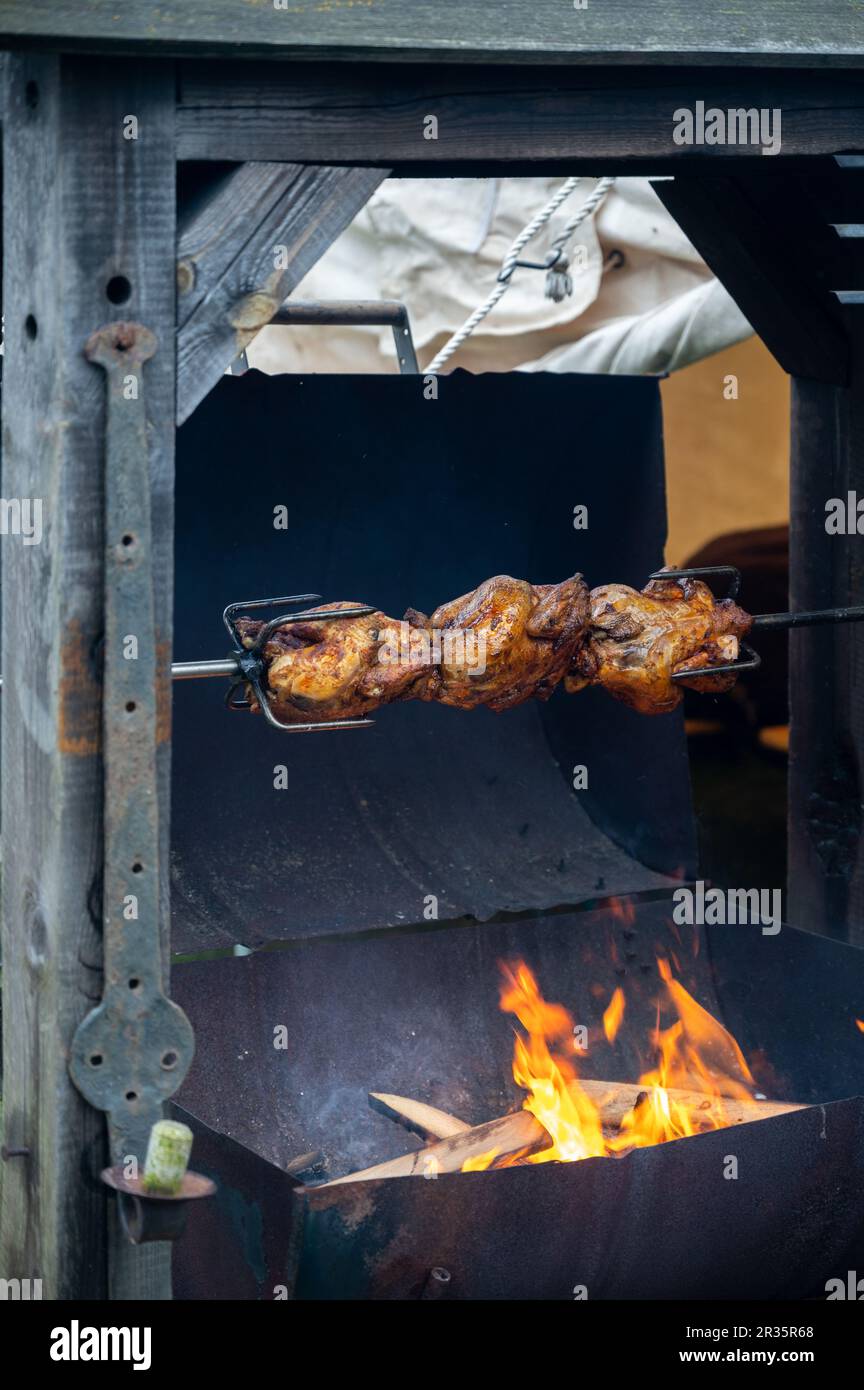 Whole chickens roasted on wooden charcoal barbecue grill outdoor in ...