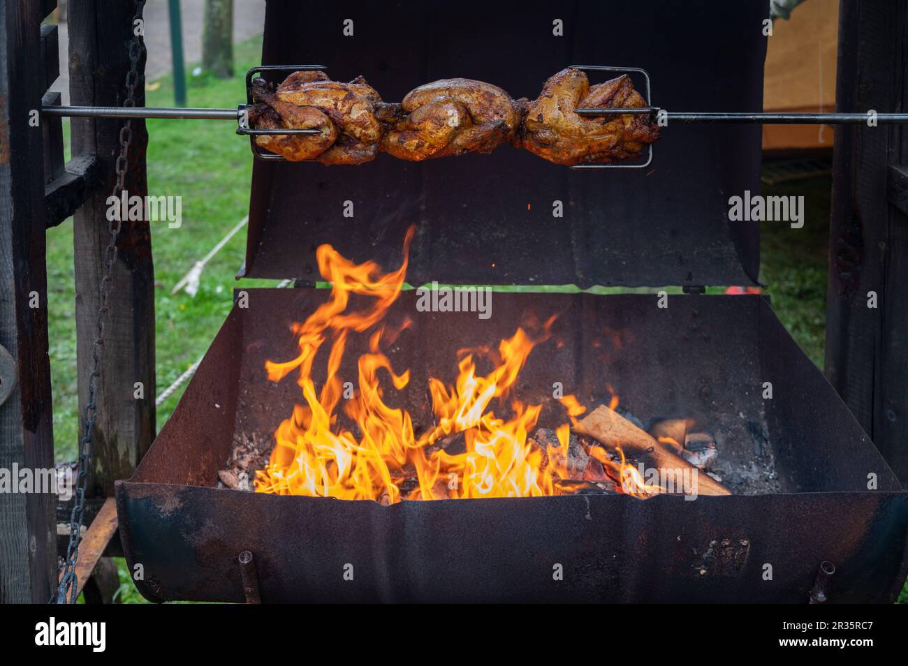 Whole chickens roasted on wooden charcoal barbecue grill outdoor in ...