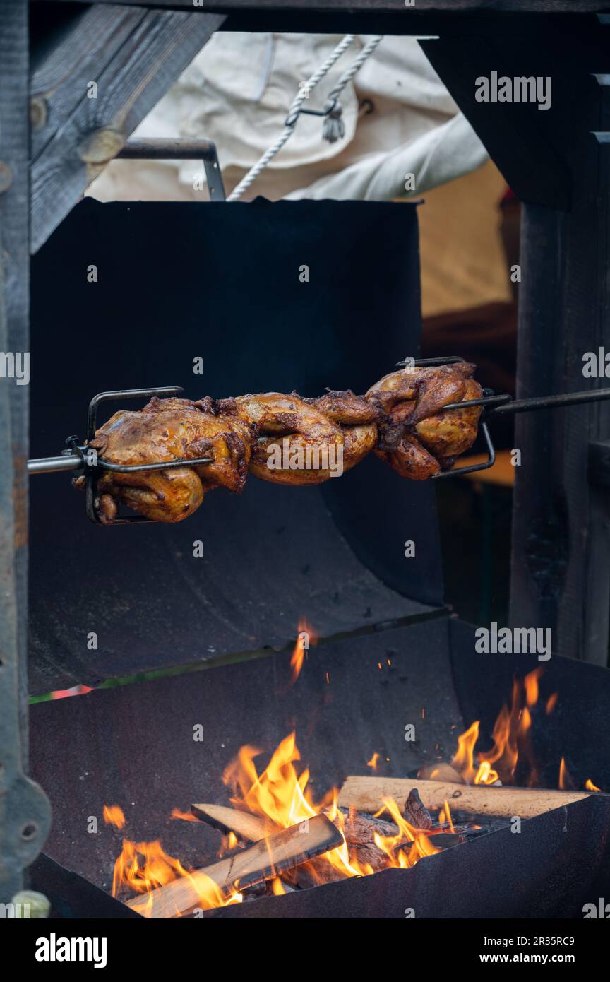 Whole chickens roasted on wooden charcoal barbecue grill outdoor in ...