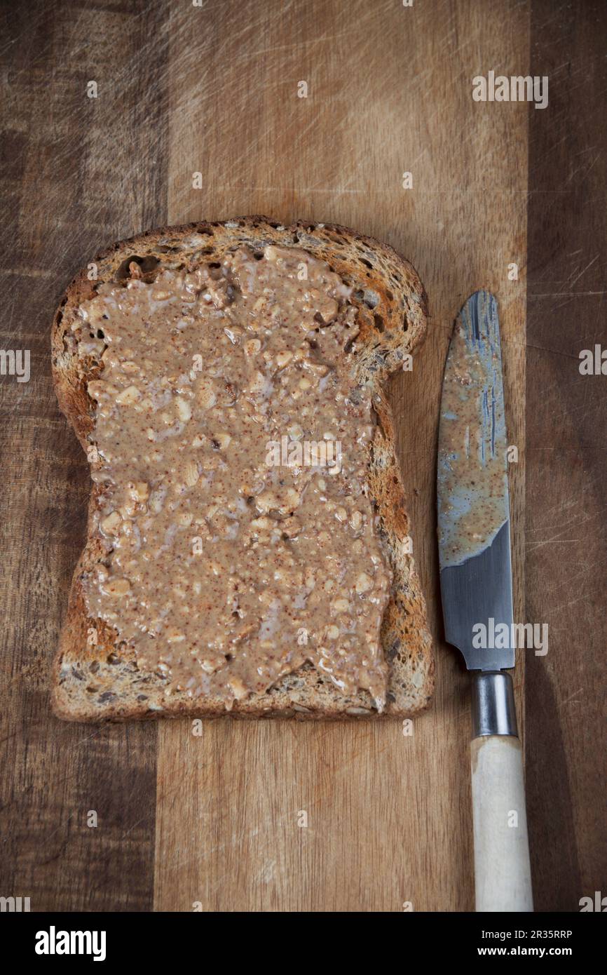Wholemeal toast with peanut butter spread on a chopping board with a ...