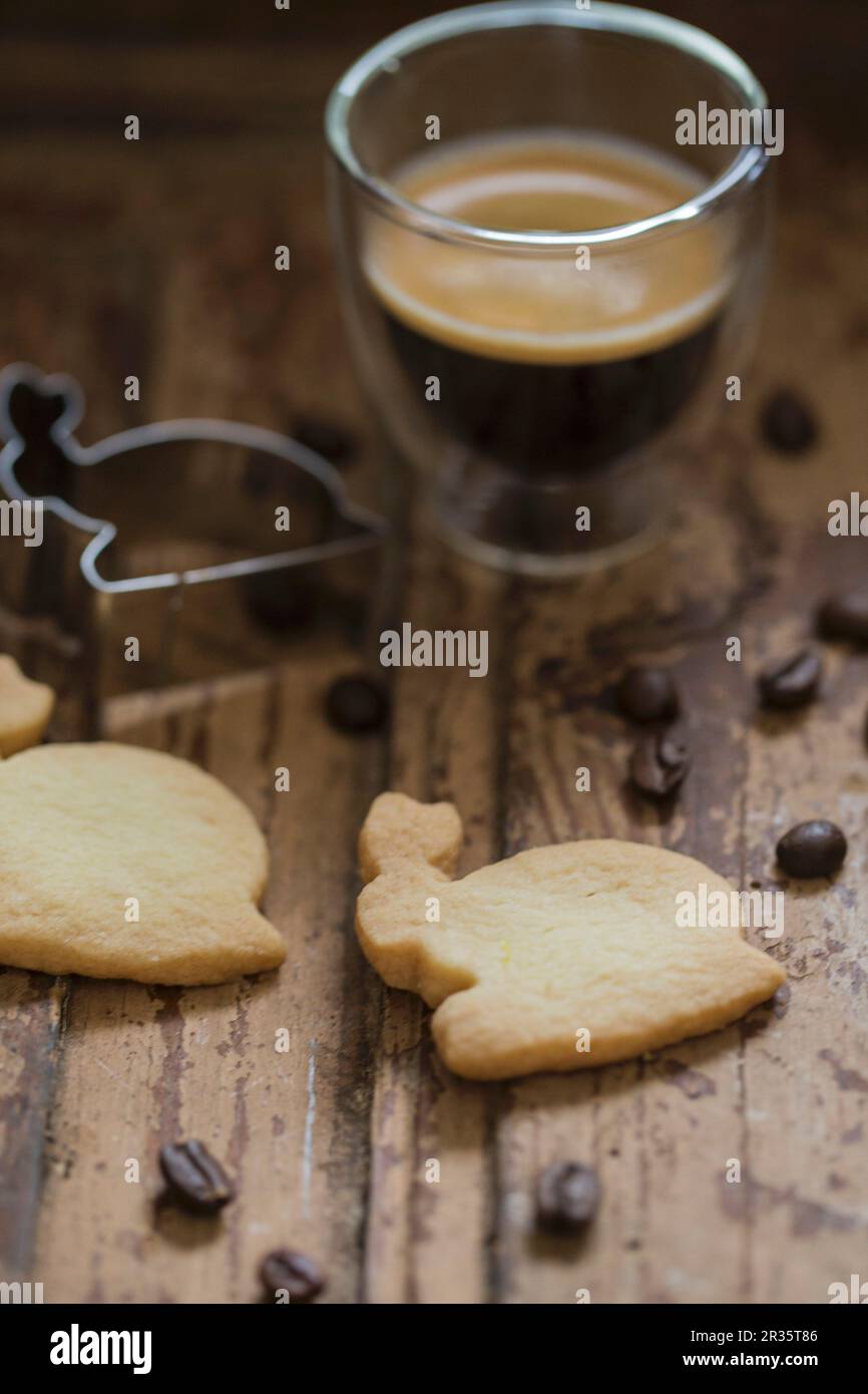 A glass of espresso with biscuit cutters and rabbit shaped biscuits ...