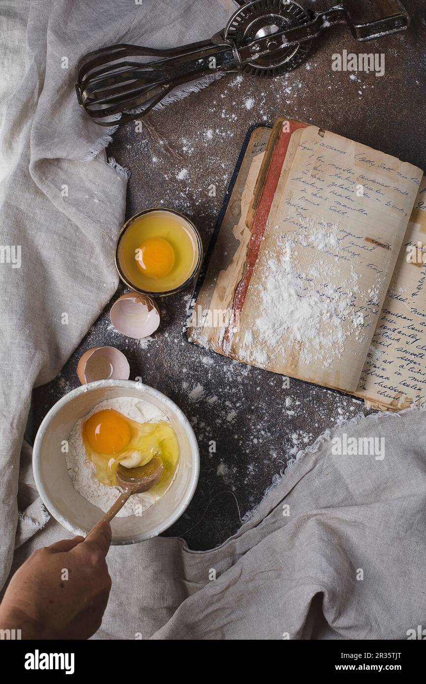 A baking scene with eggs, flour, a recipe book and a whisk Stock Photo ...