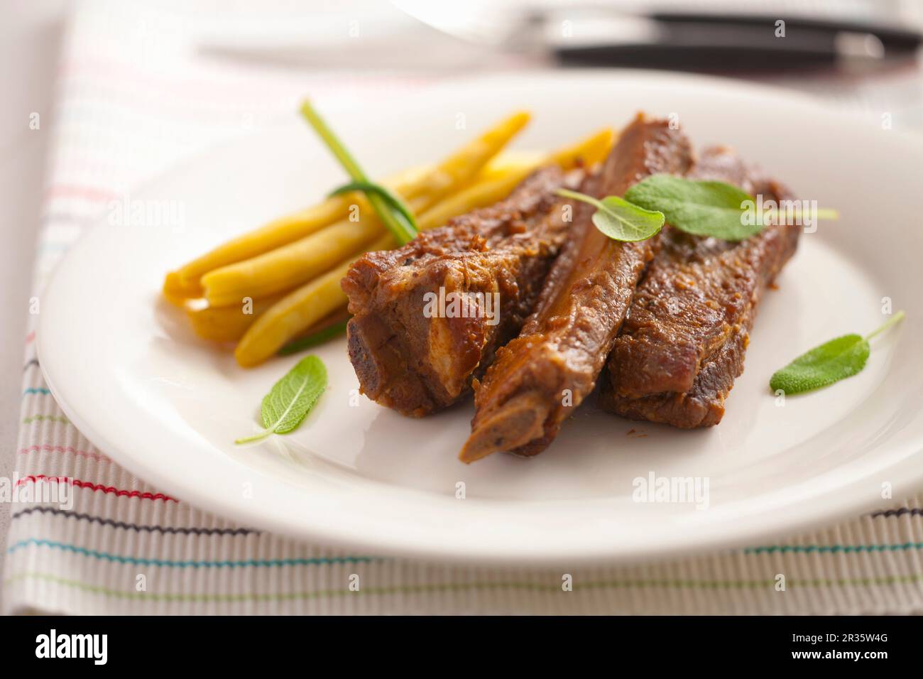 Oven-baked ribs with yellow beans and sage Stock Photo - Alamy