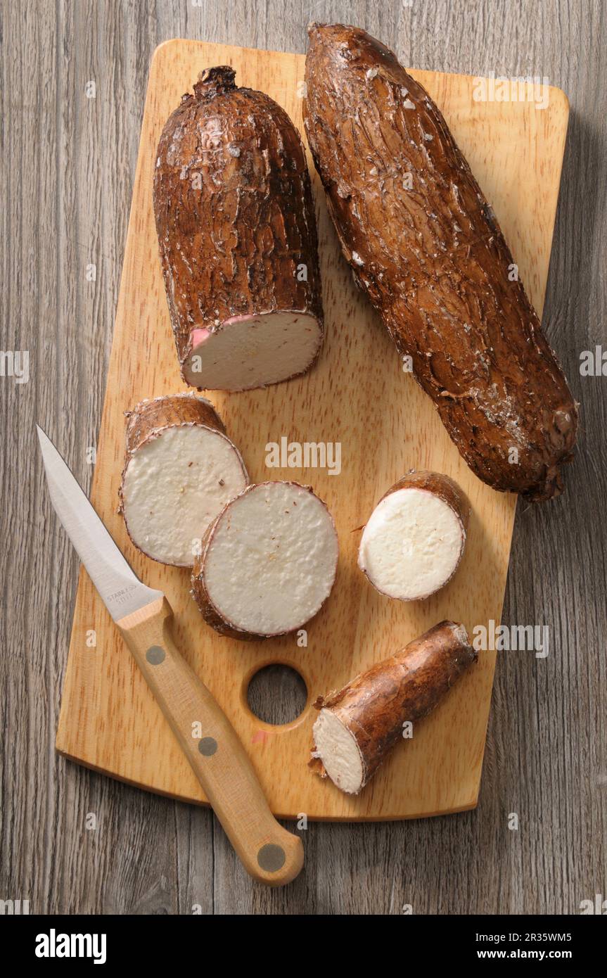 Cassava root, partially sliced, on a chopping board with a knife Stock ...