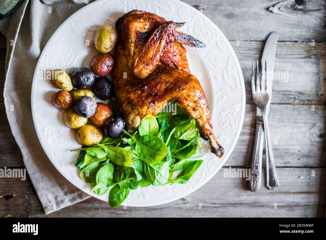Half a grilled chicken with roast potatoes and spinach (seen from above ...