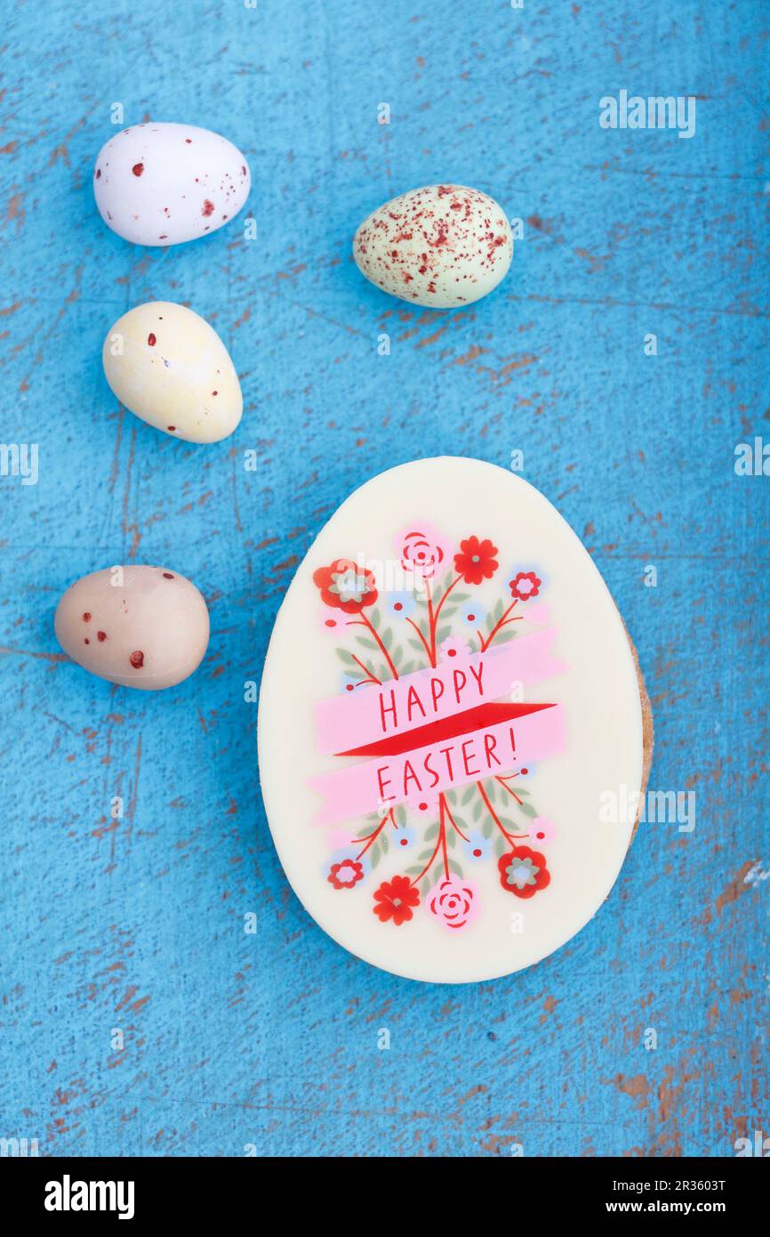 An egg-shaped Easter biscuit decorated with writing and sugar quail's ...