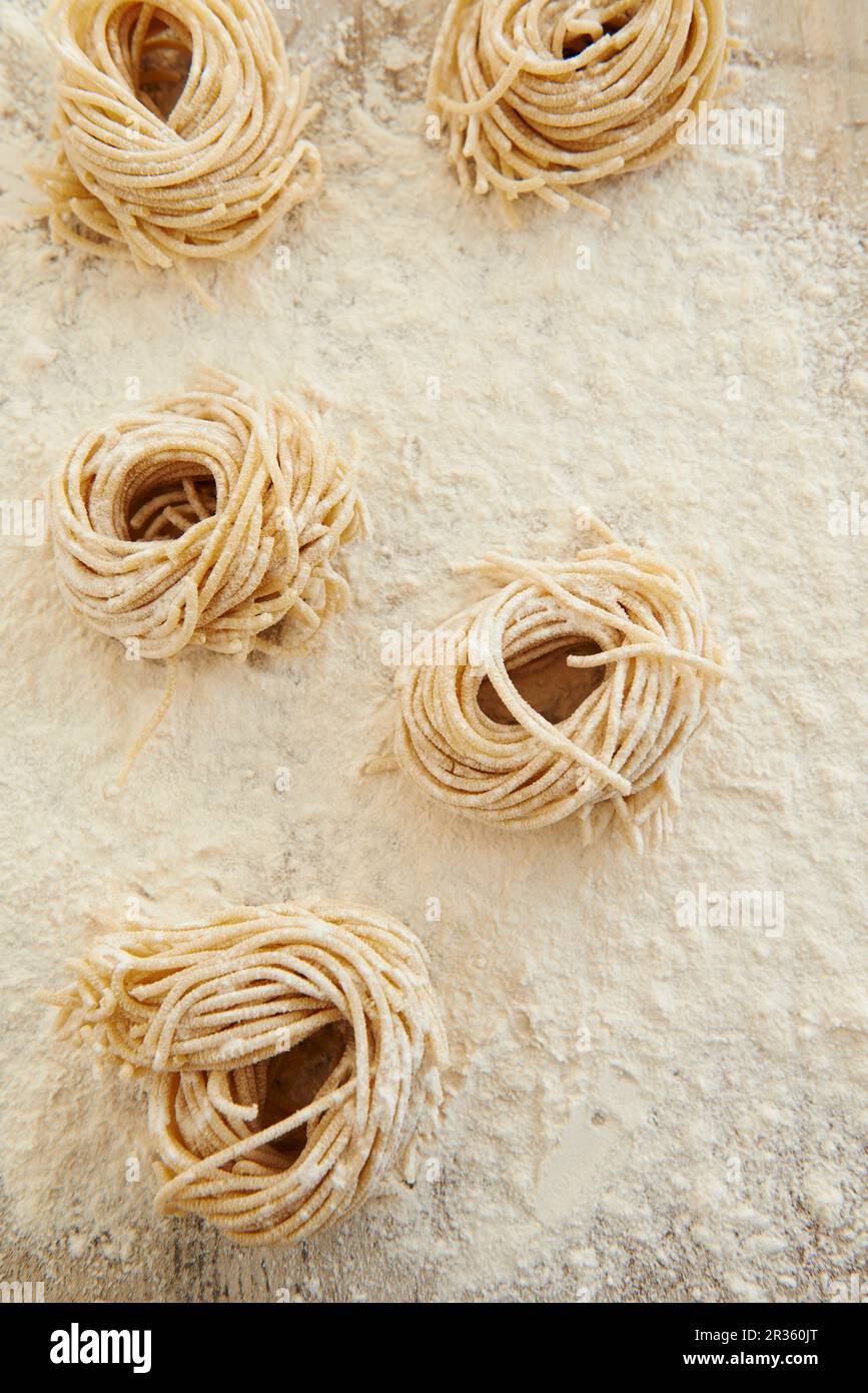 Fresh spaghetti nests on a floured work surface Stock Photo - Alamy