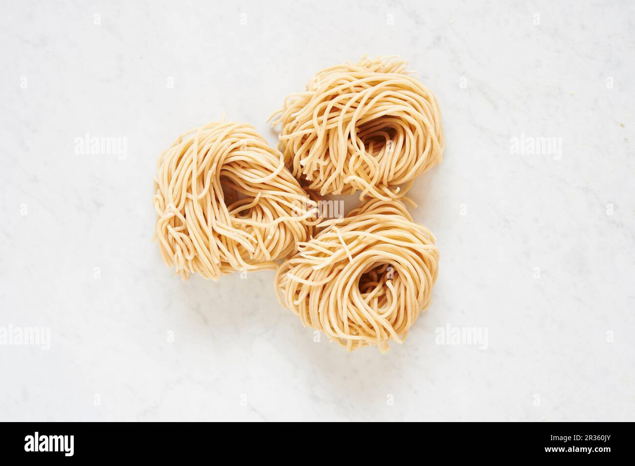 Fresh Pasta: three pasta nests on a white surface (seen from above ...