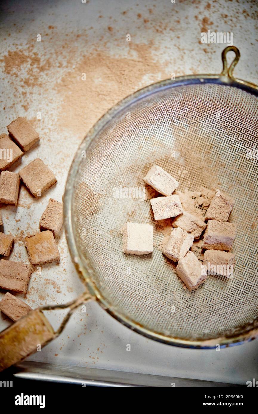 Marshmallows being dusted with cocoa powder Stock Photo - Alamy