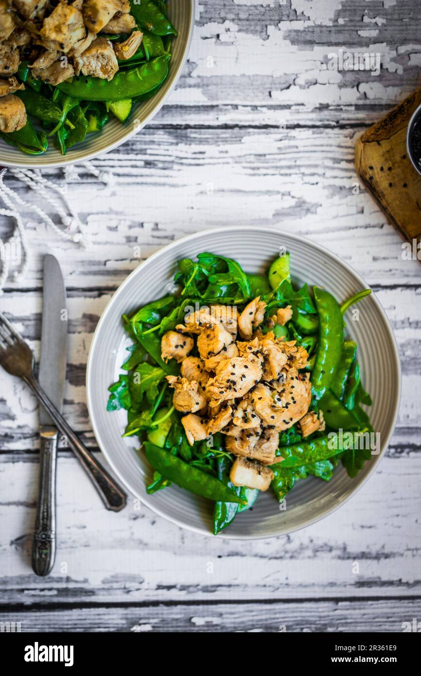 Grilled chicken with spinach, rocket and peas on rustic wooden surface ...