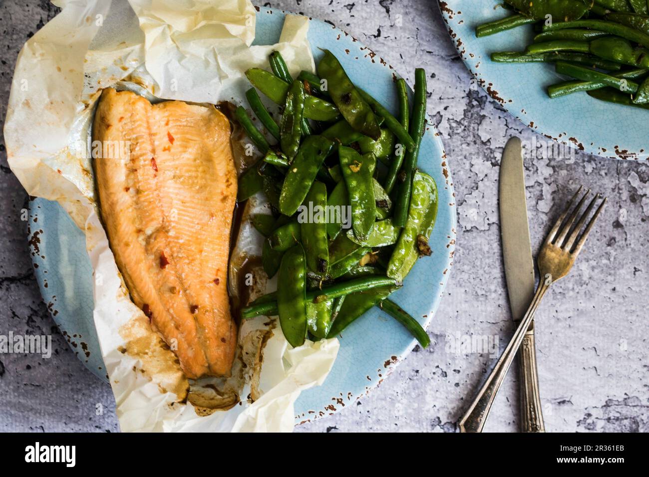 Fish baked in paper with beans and mange tout Stock Photo - Alamy
