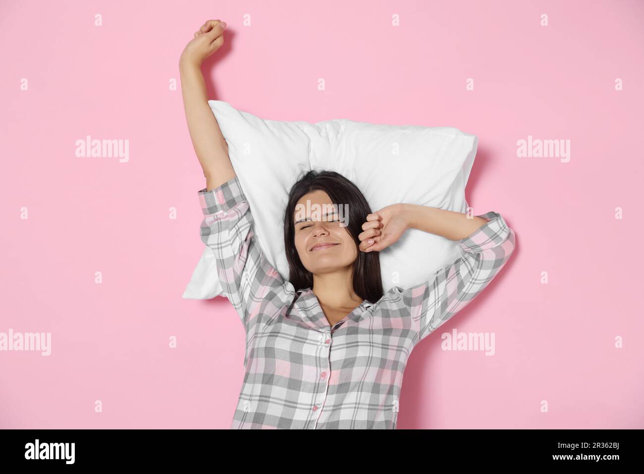 Sleepy young woman on soft pillow against pink background Stock Photo ...