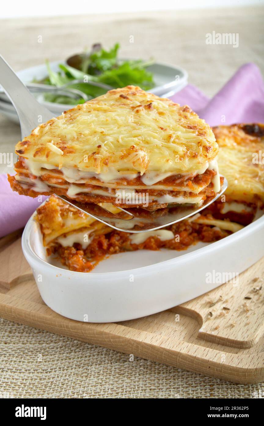 A slice of lasagne being removed from the baking dish Stock Photo - Alamy