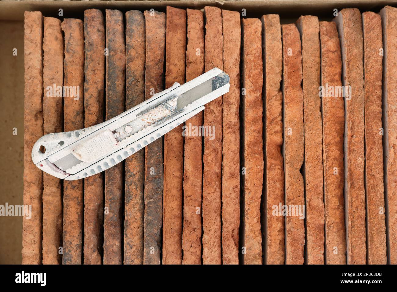 Box with many decorative bricks and utility knife, top view Stock Photo ...