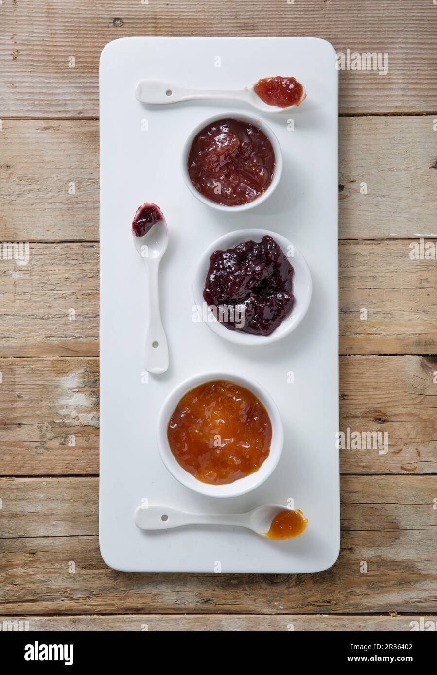 Three types of jam in bowls with spoons on a board Stock Photo - Alamy