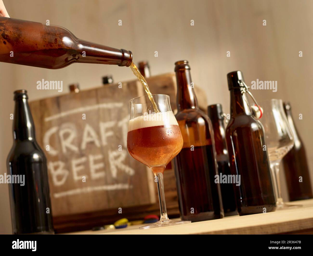 Beer being poured with open bottles of beer and a wooden crate labelled ...