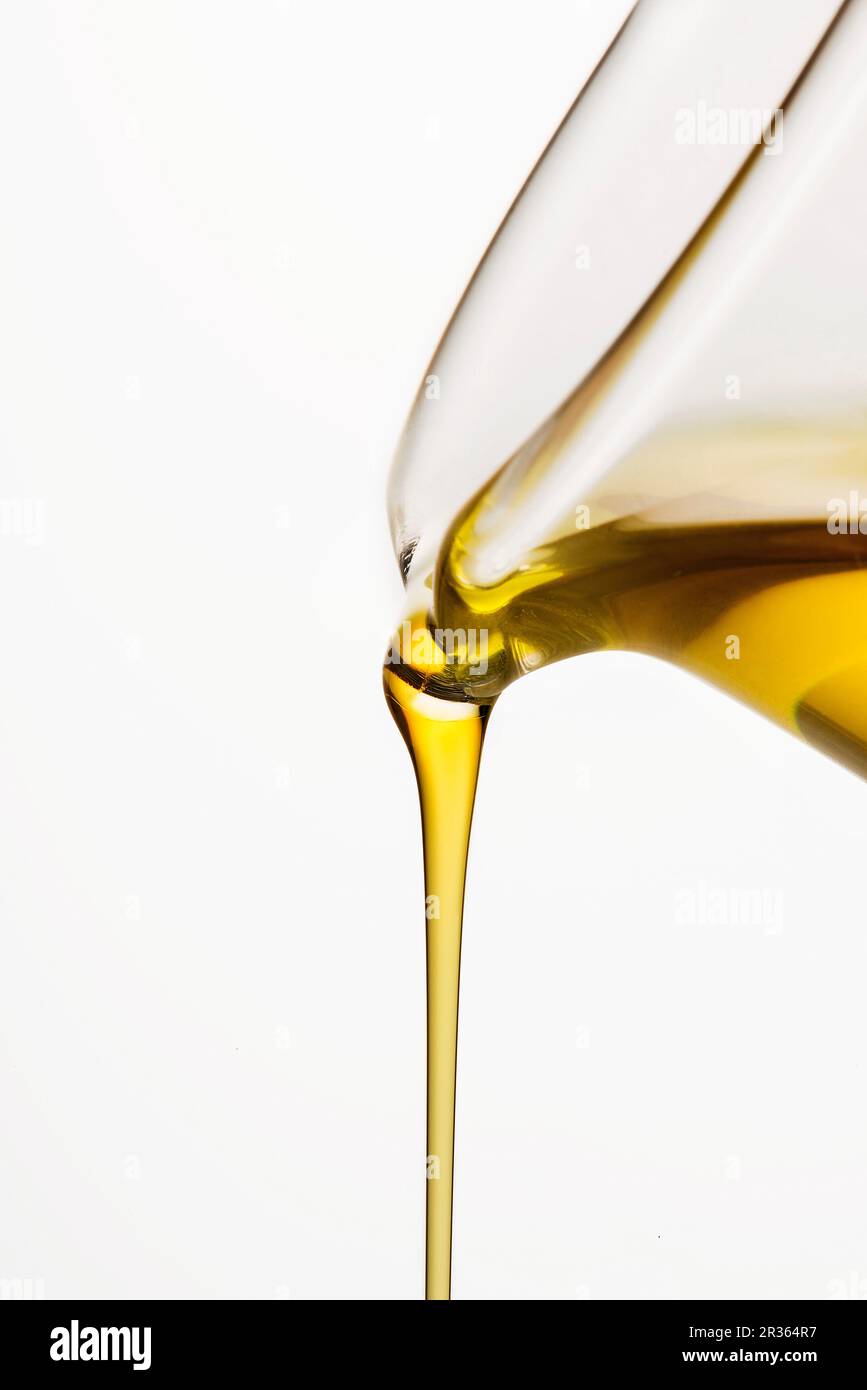 Oil being poured from a carafe against a white background Stock Photo ...