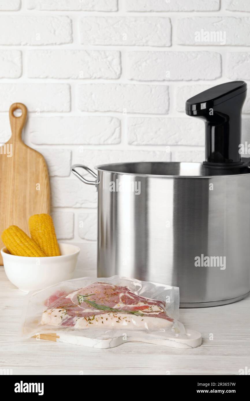 Thermal immersion circulator in pot and vacuum packed meat on white ...