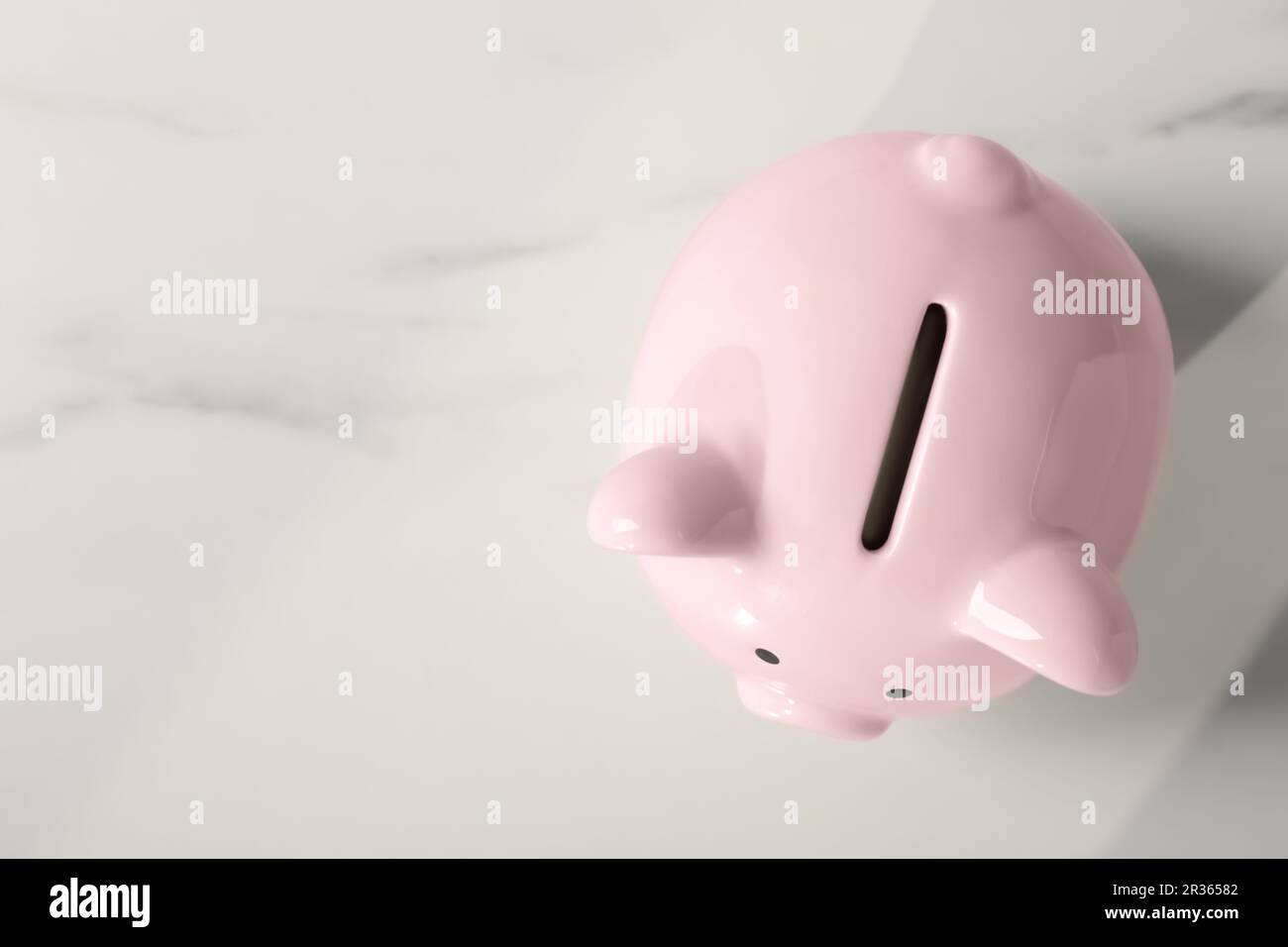 Ceramic piggy bank on white marble table, top view. Space for text ...