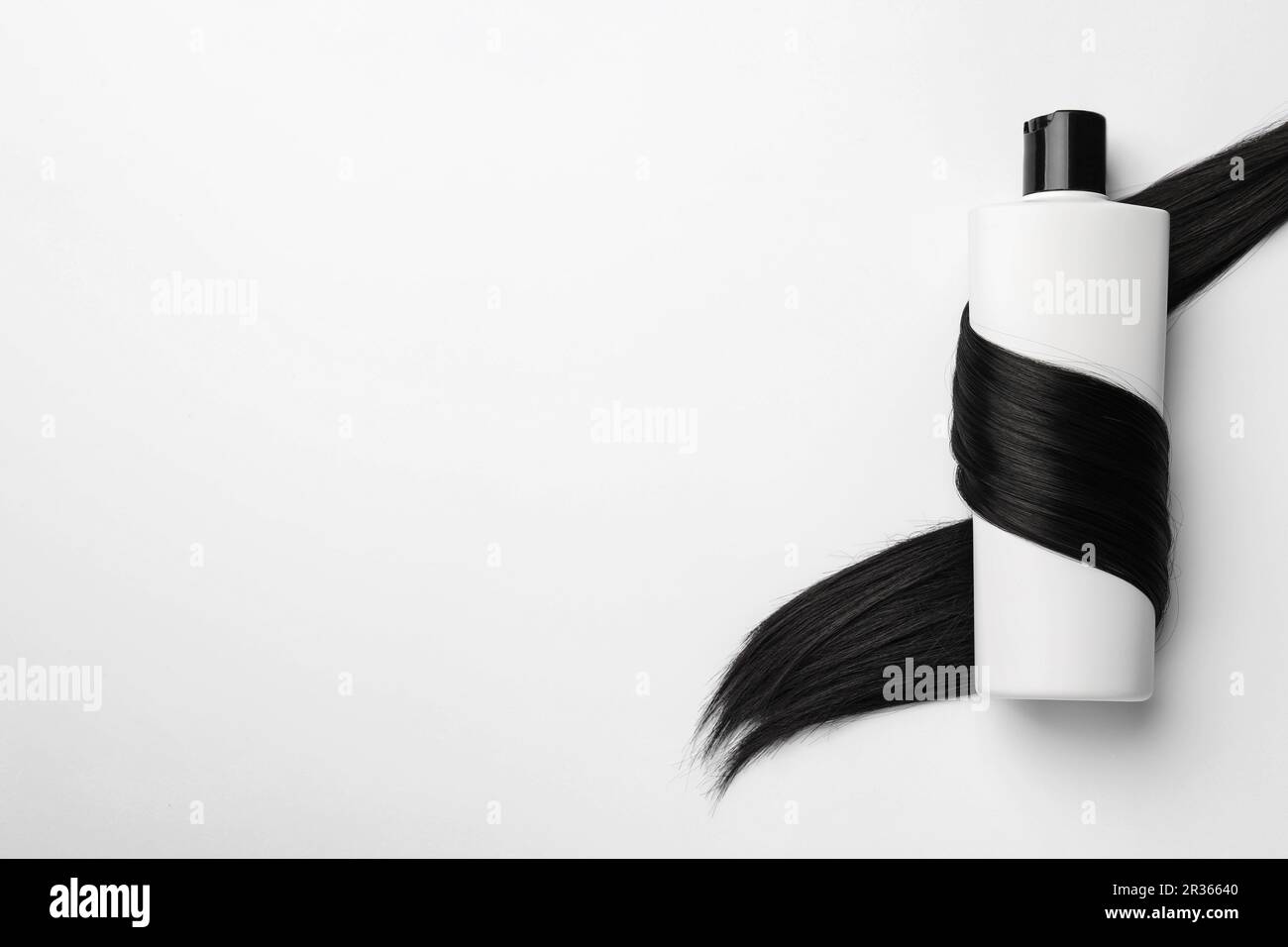 Shampoo bottle wrapped in lock of hair on white background, top view ...