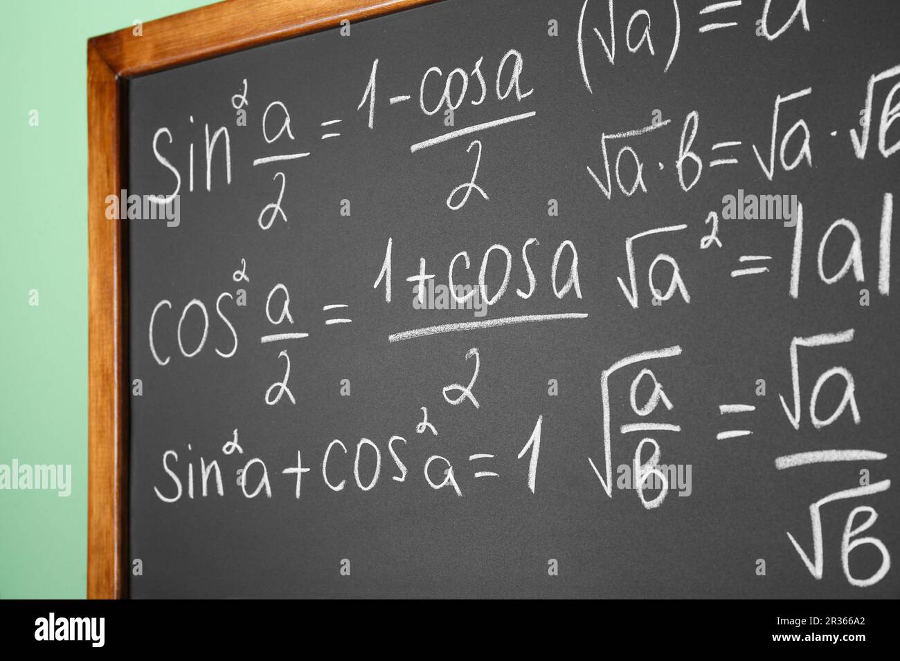 Chalkboard with many different math formulas on green wall, closeup ...