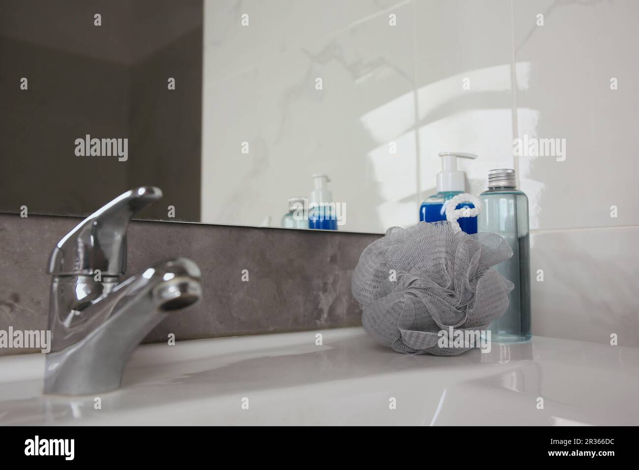 Grey shower puff and cosmetic products on washbasin in bathroom Stock ...