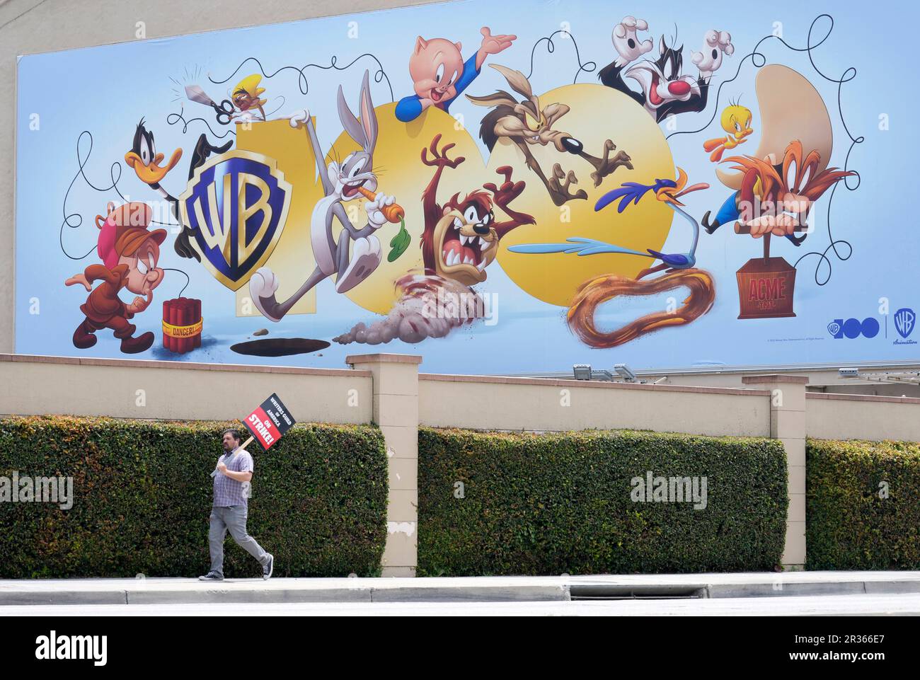 A picketer walks underneath a billboard highlighting Warner Bros ...