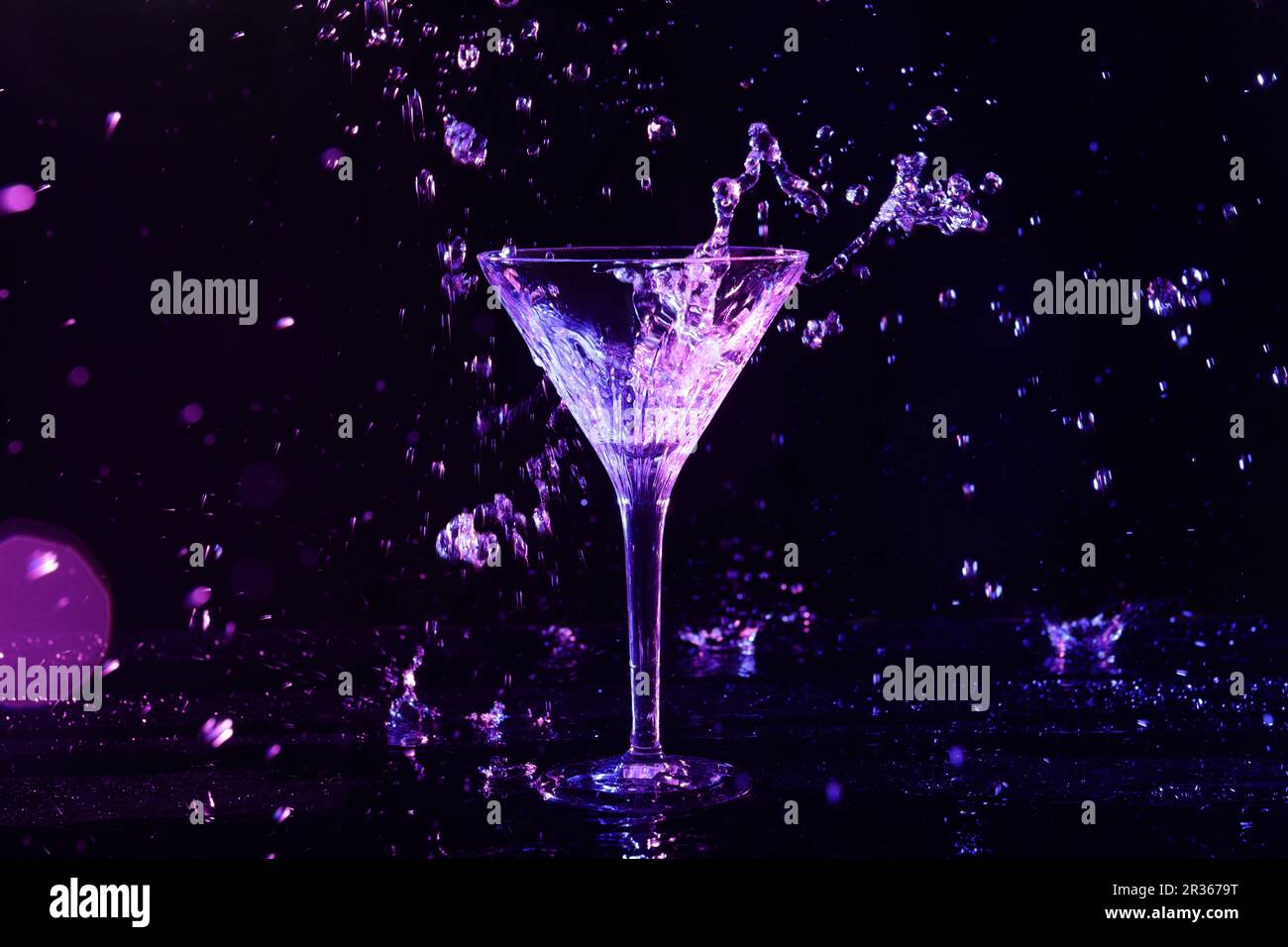 Glass of martini and splashes in neon lights on dark background, bokeh ...