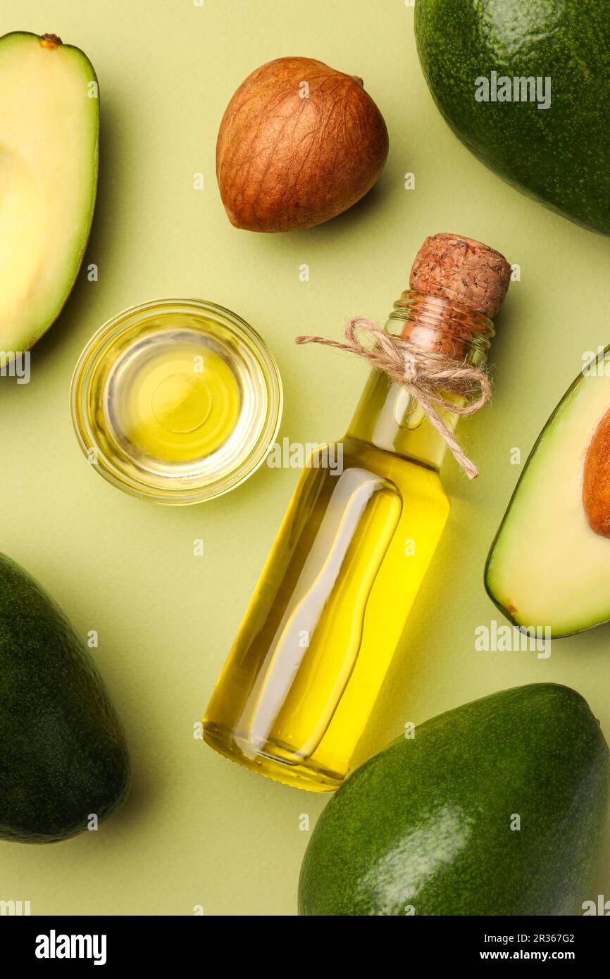 Cooking oil and fresh avocados on light green background, flat lay ...