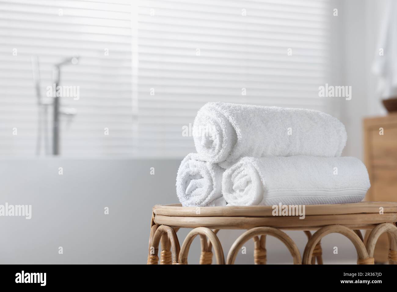 Rolled bath towels on wicker table in bathroom. Space for text Stock ...