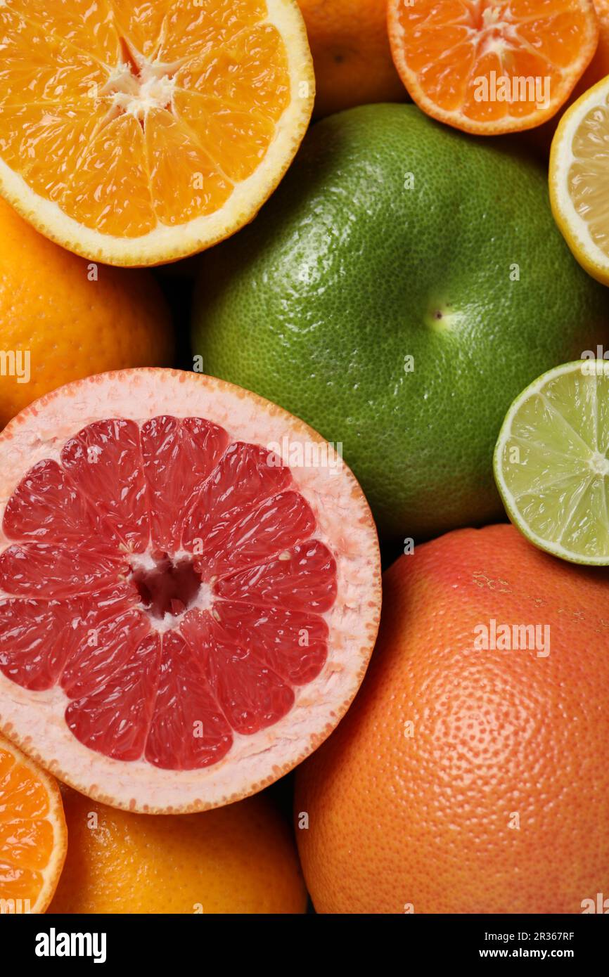 Different fresh whole and cut citrus fruits as background, top view ...