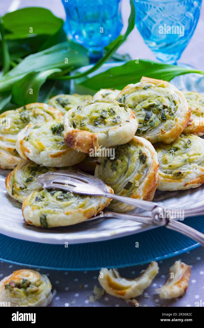 Vegetarian wild garlic pastries on a plate with a pair of pastry tongs ...
