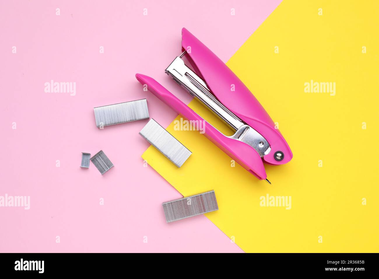 New bright stapler with staples on color background, fat lay. School ...