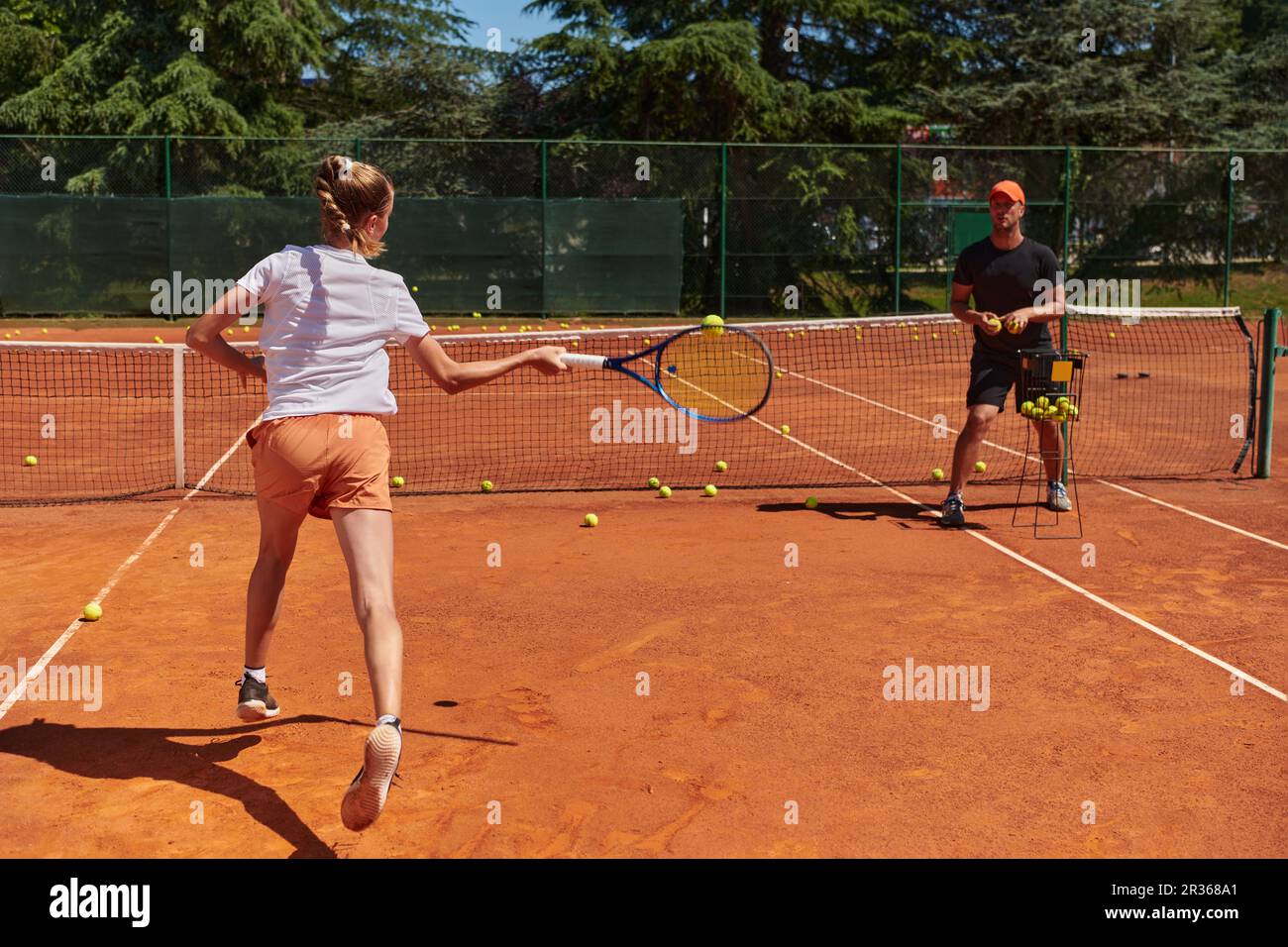 A professional tennis player and her coach training on a sunny day at ...