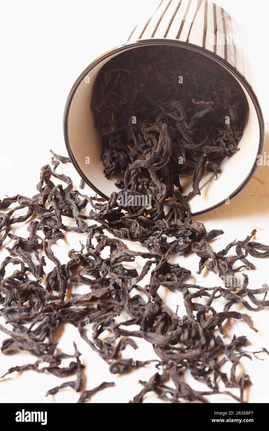 Black tea leave spilling out of a cup Stock Photo - Alamy