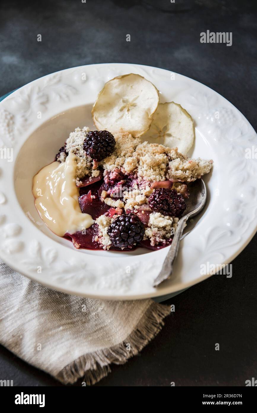 Blackberry and apple crumble served with custard Stock Photo - Alamy