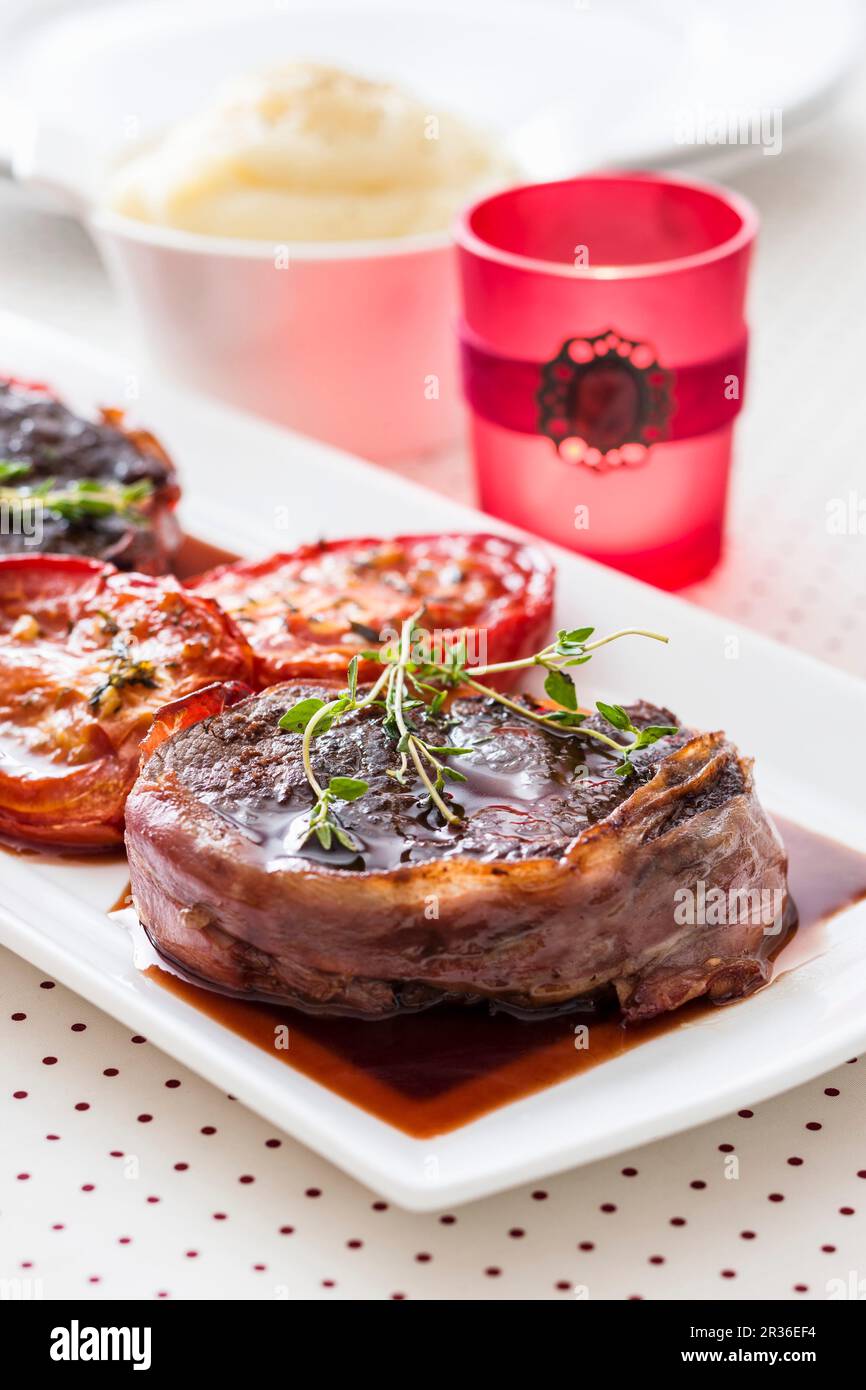 Beef fillet wrapped in bacon with grilled tomatoes Stock Photo - Alamy