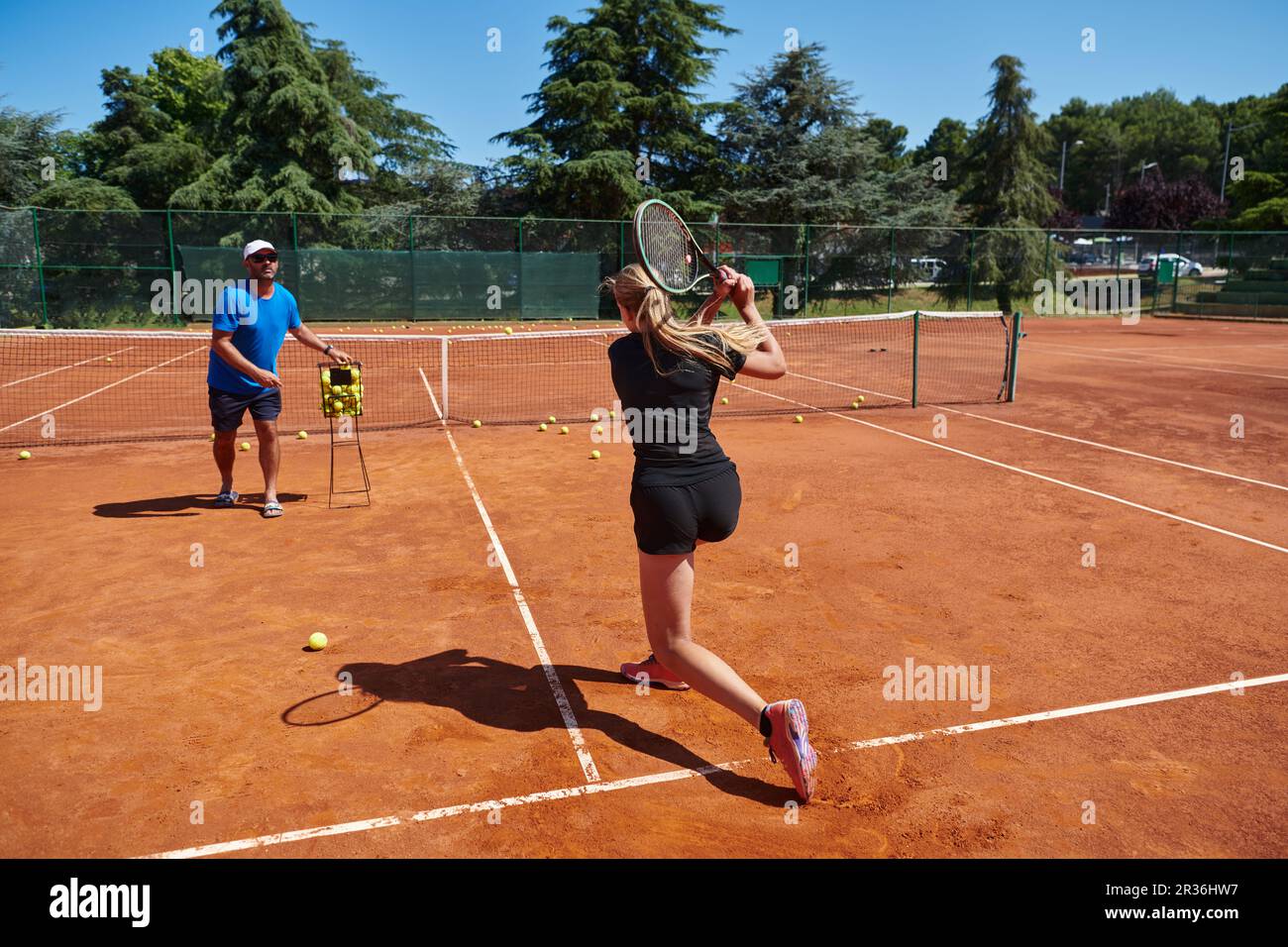 A professional tennis player and her coach training on a sunny day at ...