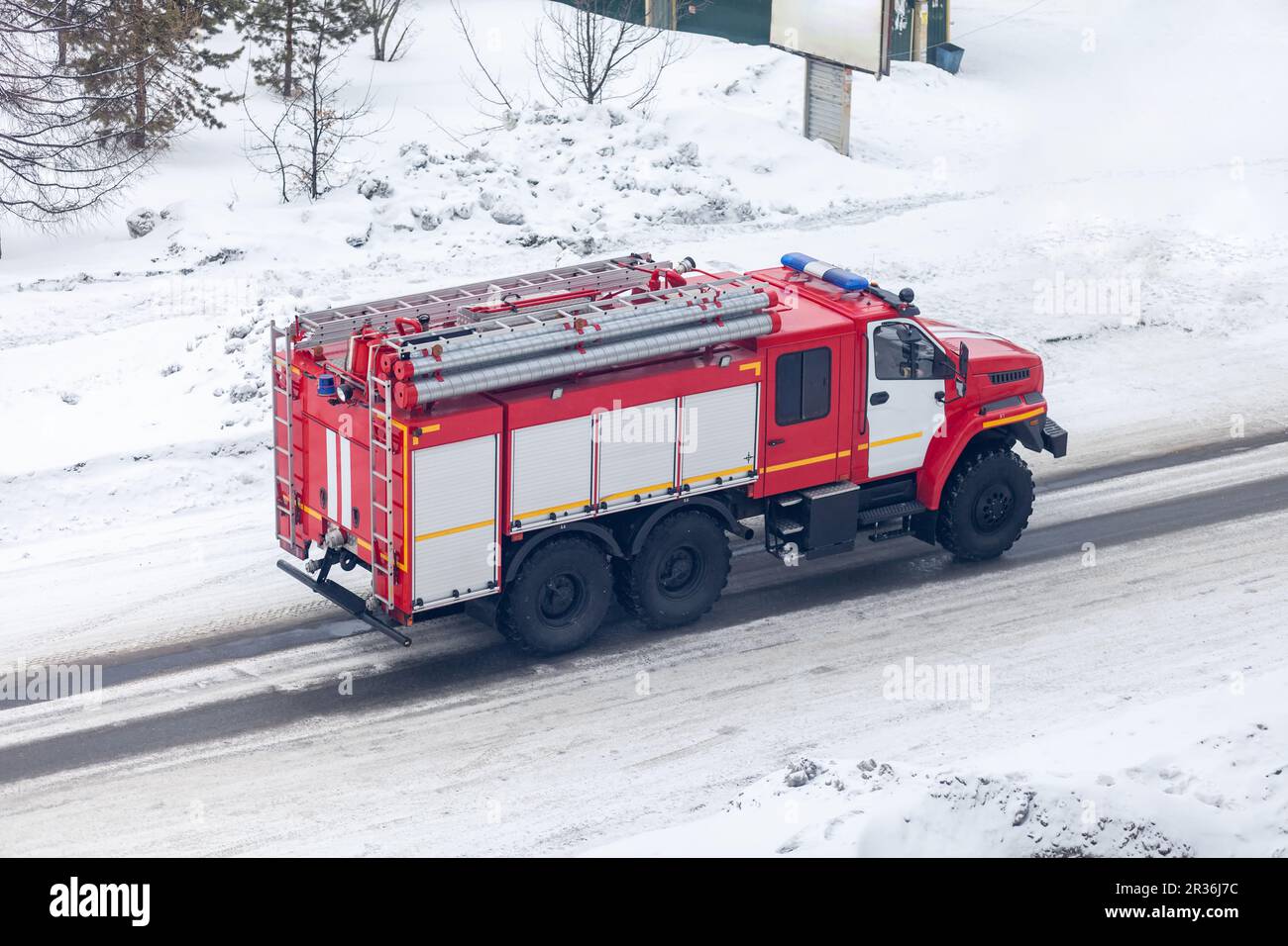 A red fire truck or Fire engine drives down a snowy street in winter to ...