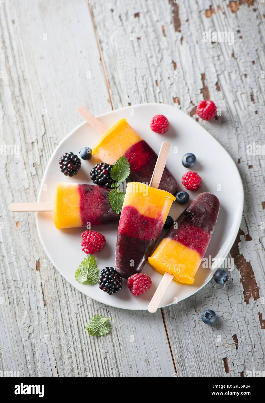 Tri-coloured berry and mango ice lollies Stock Photo - Alamy