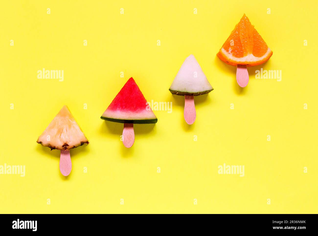 Various sliced fruits on sticks on a yellow surface Stock Photo - Alamy