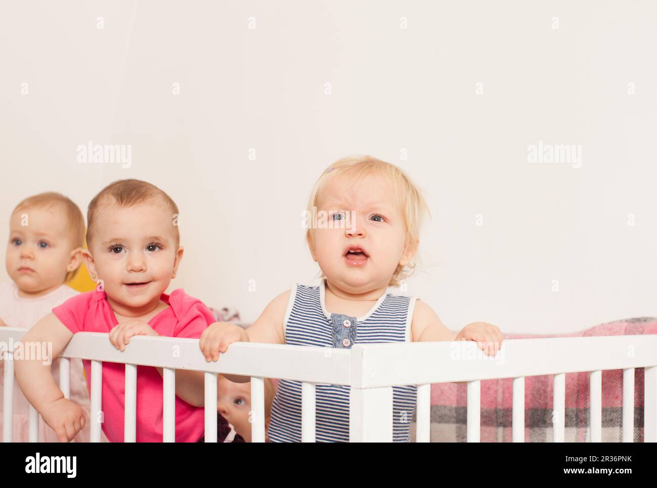 Three baby girls in the crib Stock Photo - Alamy
