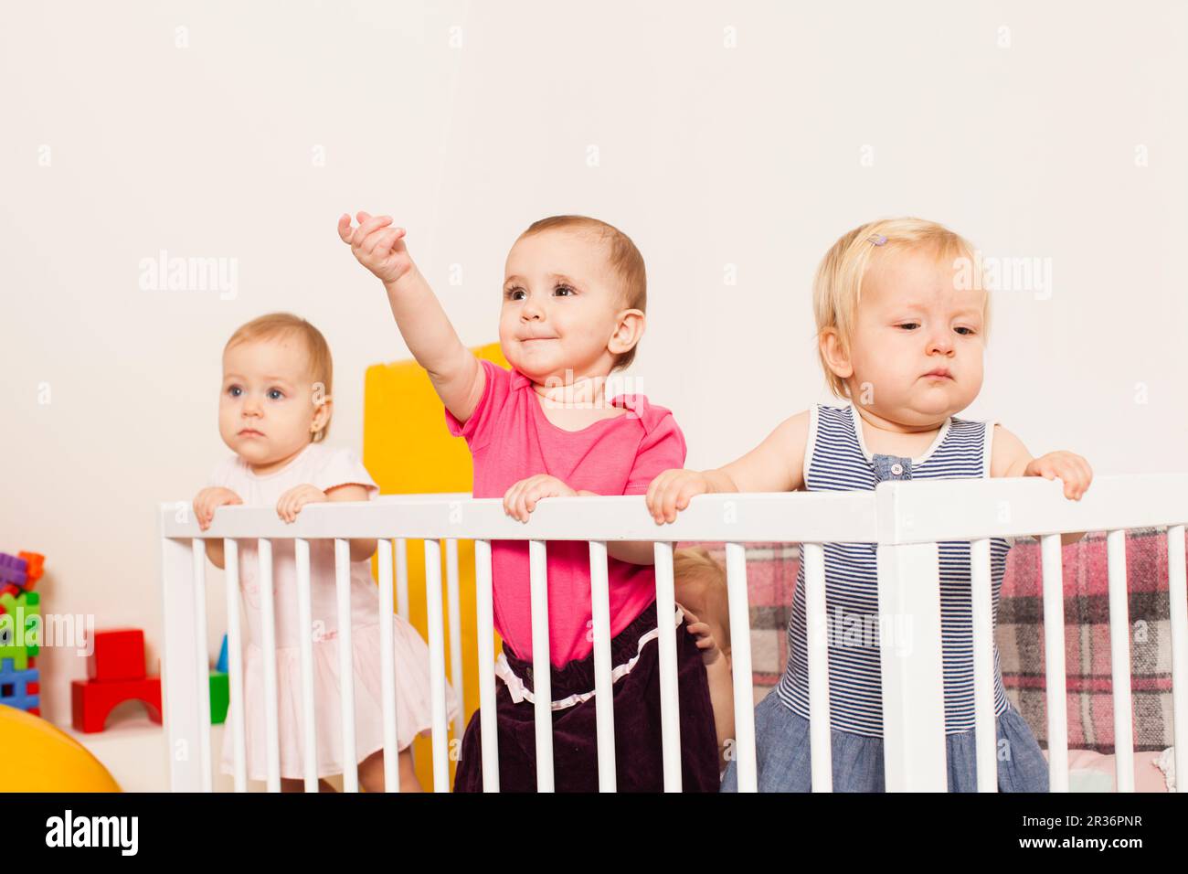 Three baby girls in the crib Stock Photo - Alamy