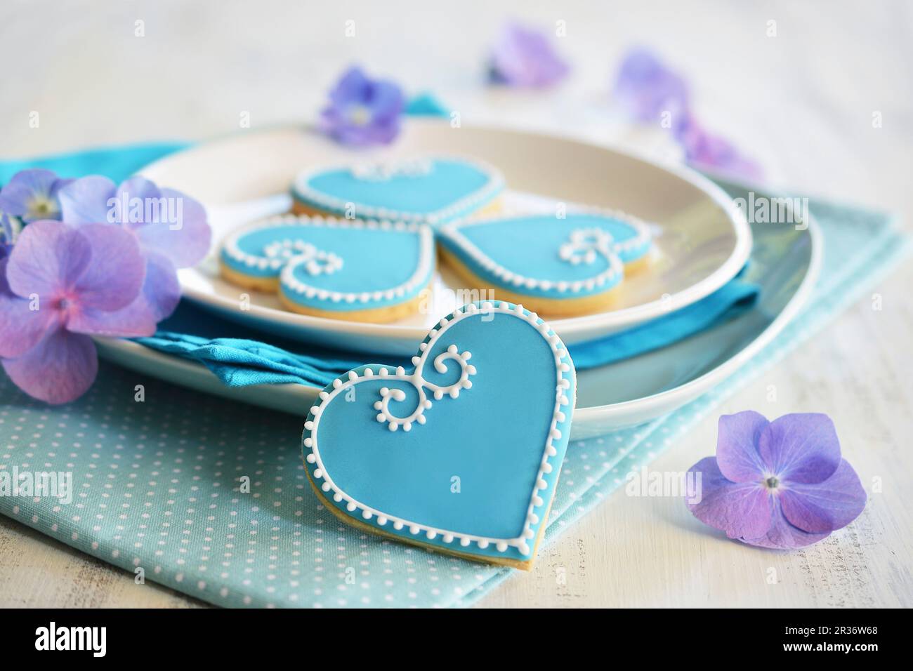Heart-shaped biscuits decorated with blue and white icing served on a ...